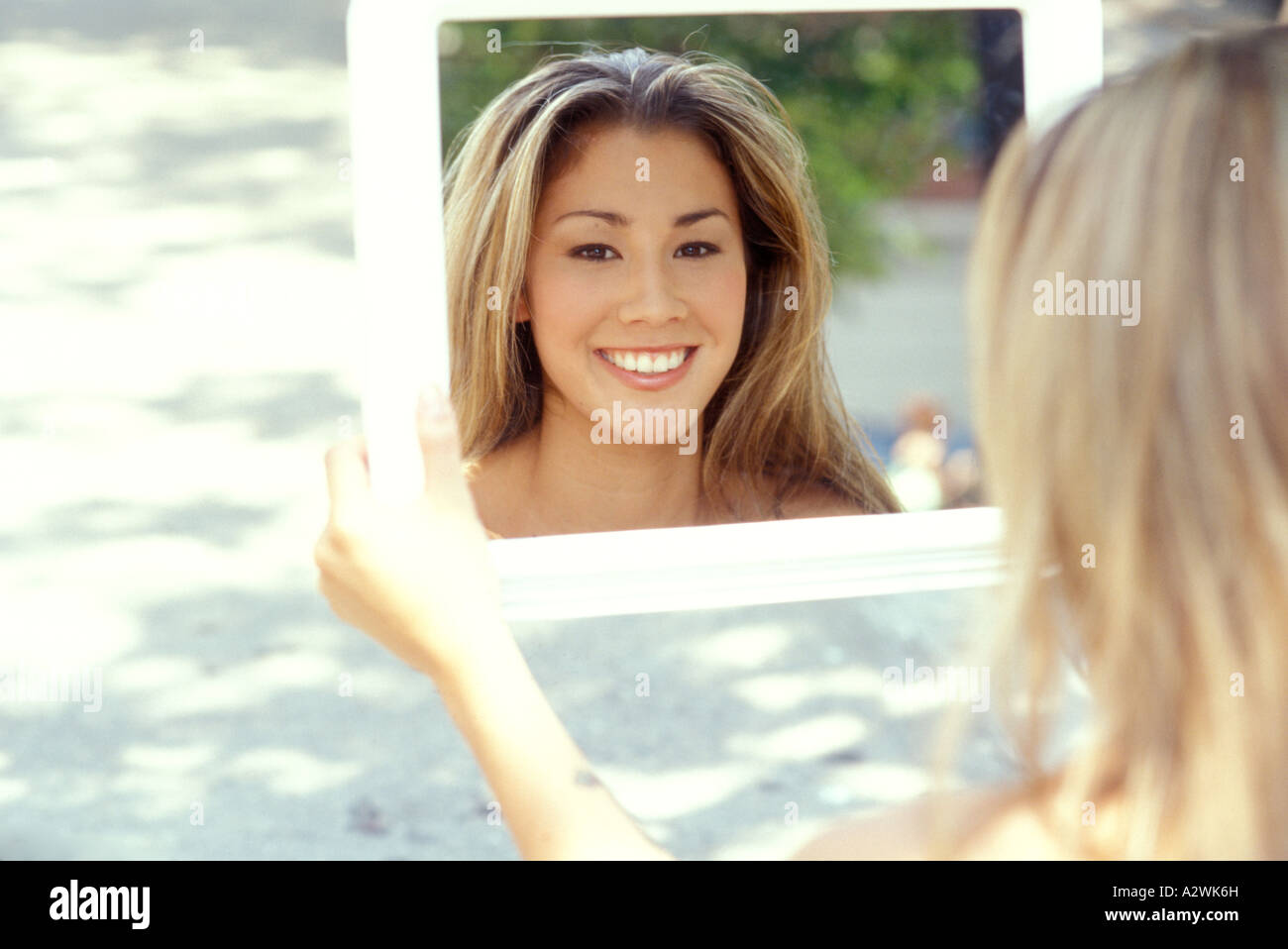 Young woman looking at mirror, smiling Stock Photo - Alamy