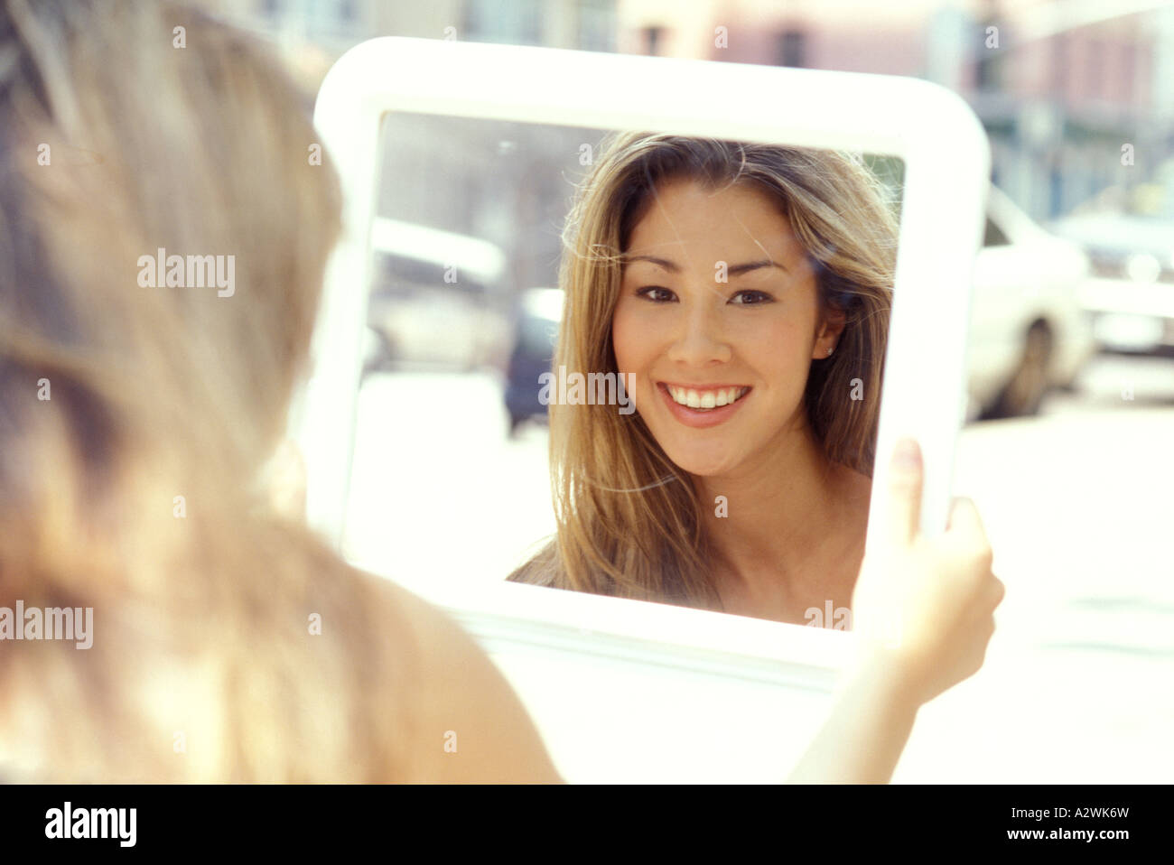 Young woman holding mirror, smiling Stock Photo - Alamy