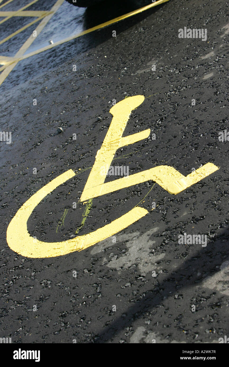 yellow freshly painted disabled sign on tarmac parking space on wet ...