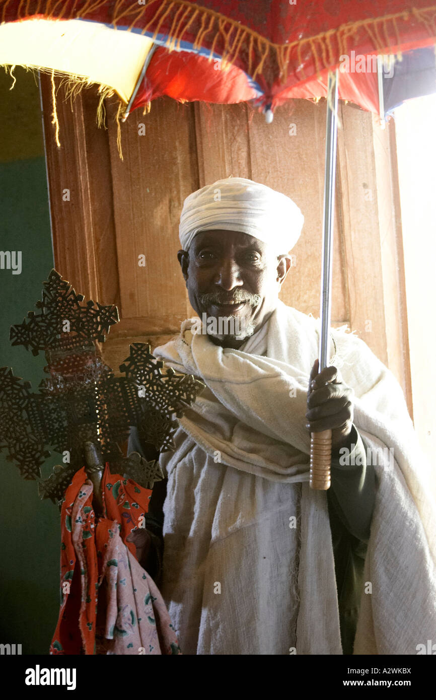 Old priest with metal cross and religious umbrella in Debre Maryam or ...