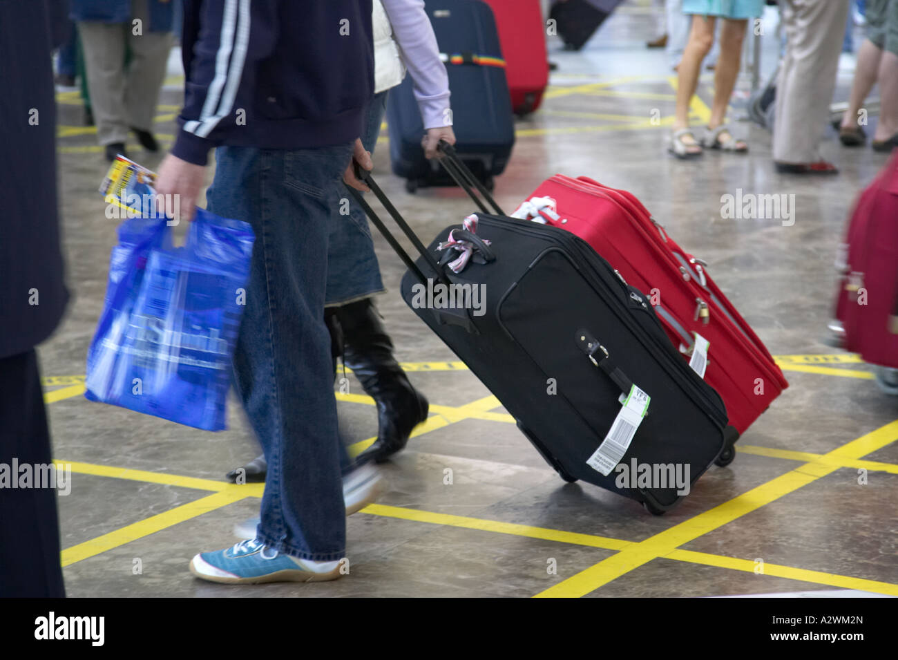 male and female passengers pull wheeled luggage with flight tags on out ...