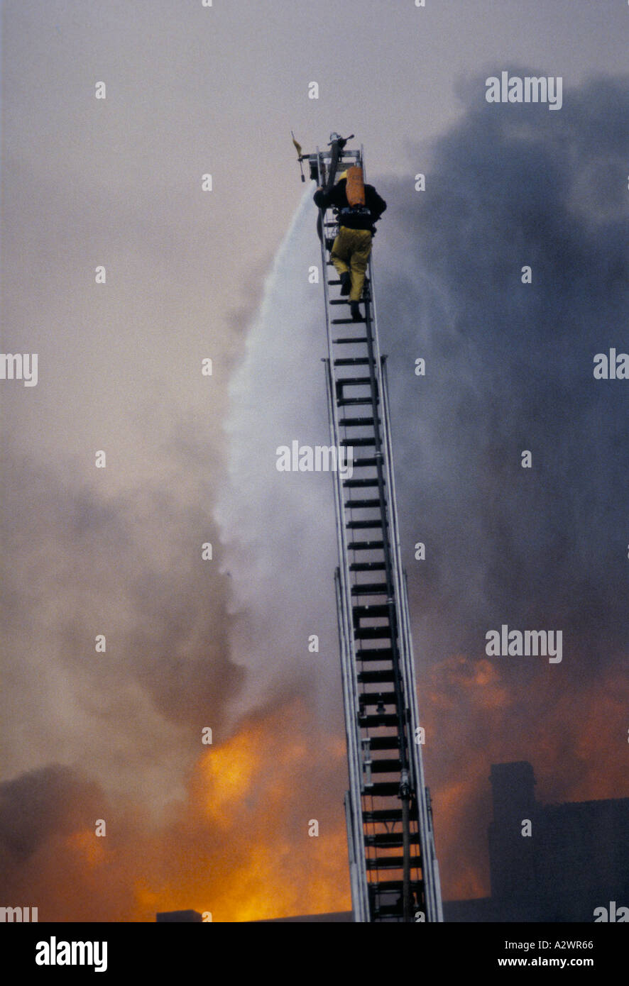 fire fighters douse fire using water cannon at the top of ladder ...