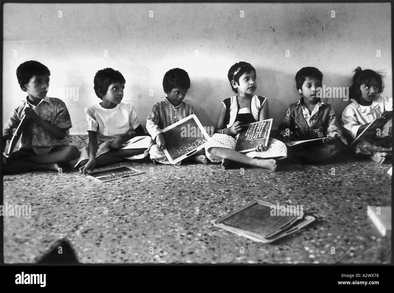 Children sit in a row holding their blackboards at the Ches Ashram for ...