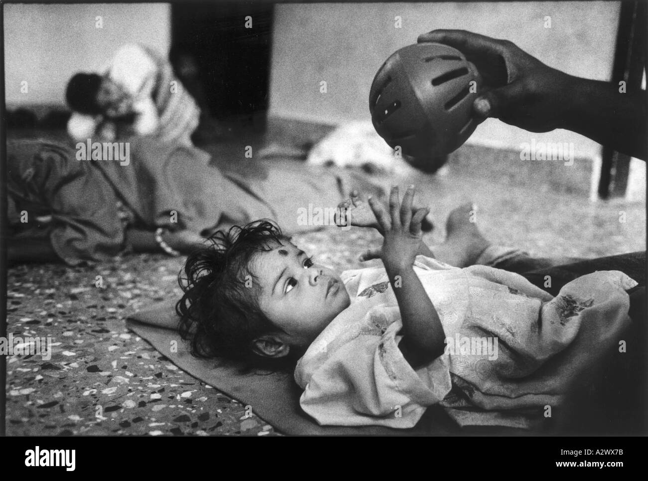 A carer playing ball with a little girl at Ches Ashram for Aids orphans ...