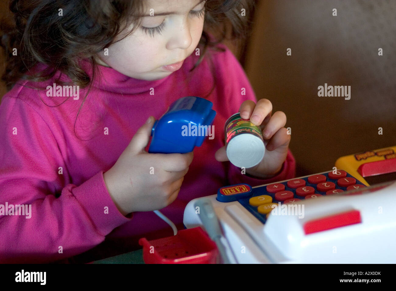 Girl age 3 scanning item at toy cash register. Plainfield Illinois IL ...