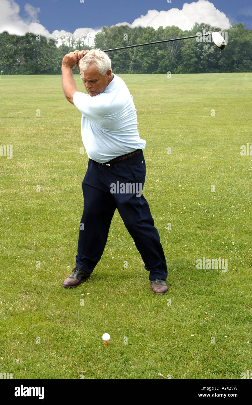 An adult male swinging a wood on the driving range at a golf course ...