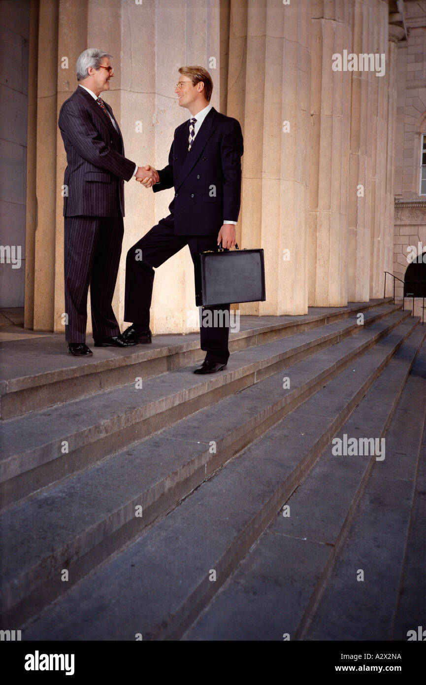 Montage image of two men on building steps. Handshake Stock Photo - Alamy