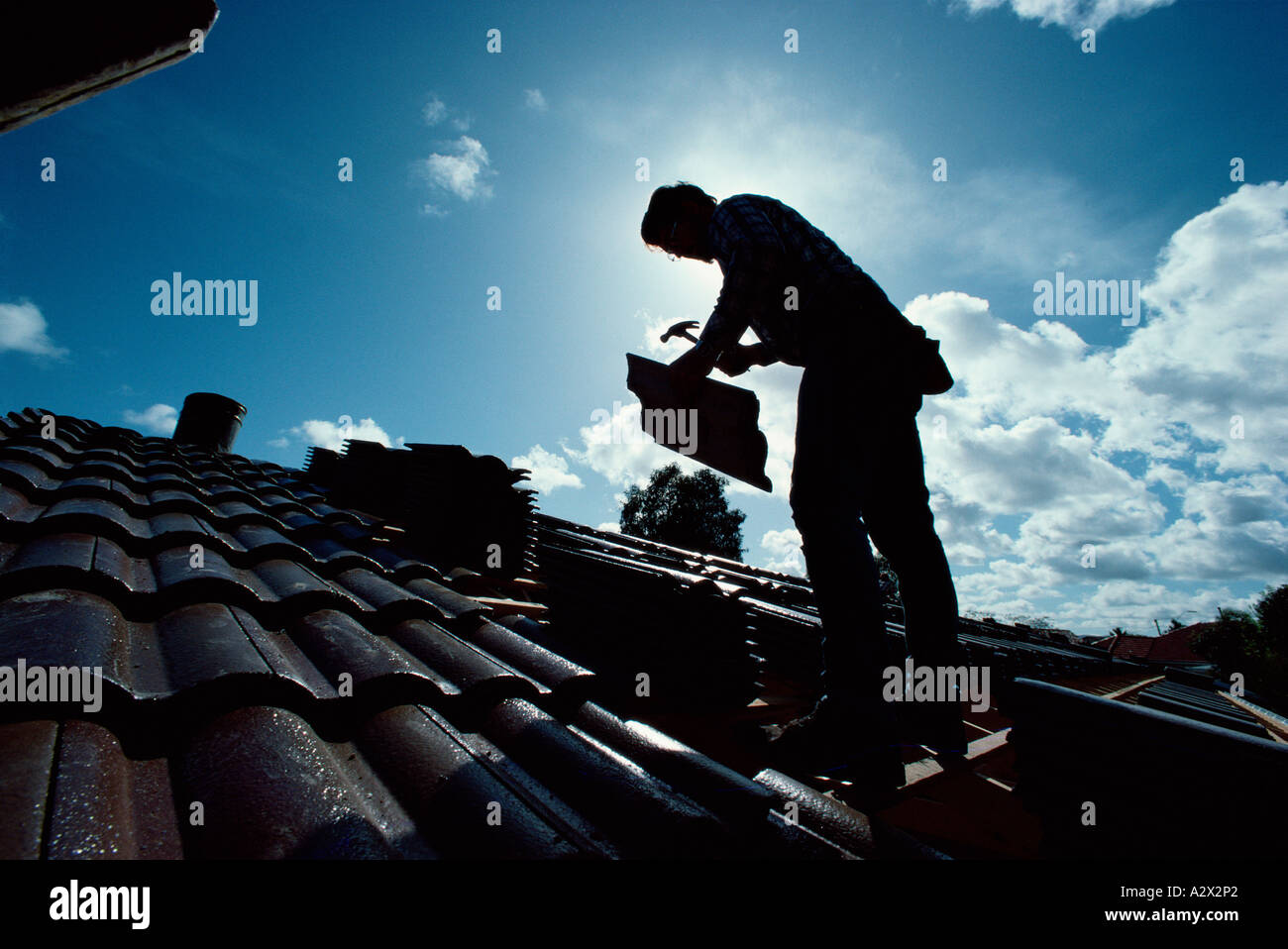 Building roof construction. Man tiling roof Stock Photo - Alamy