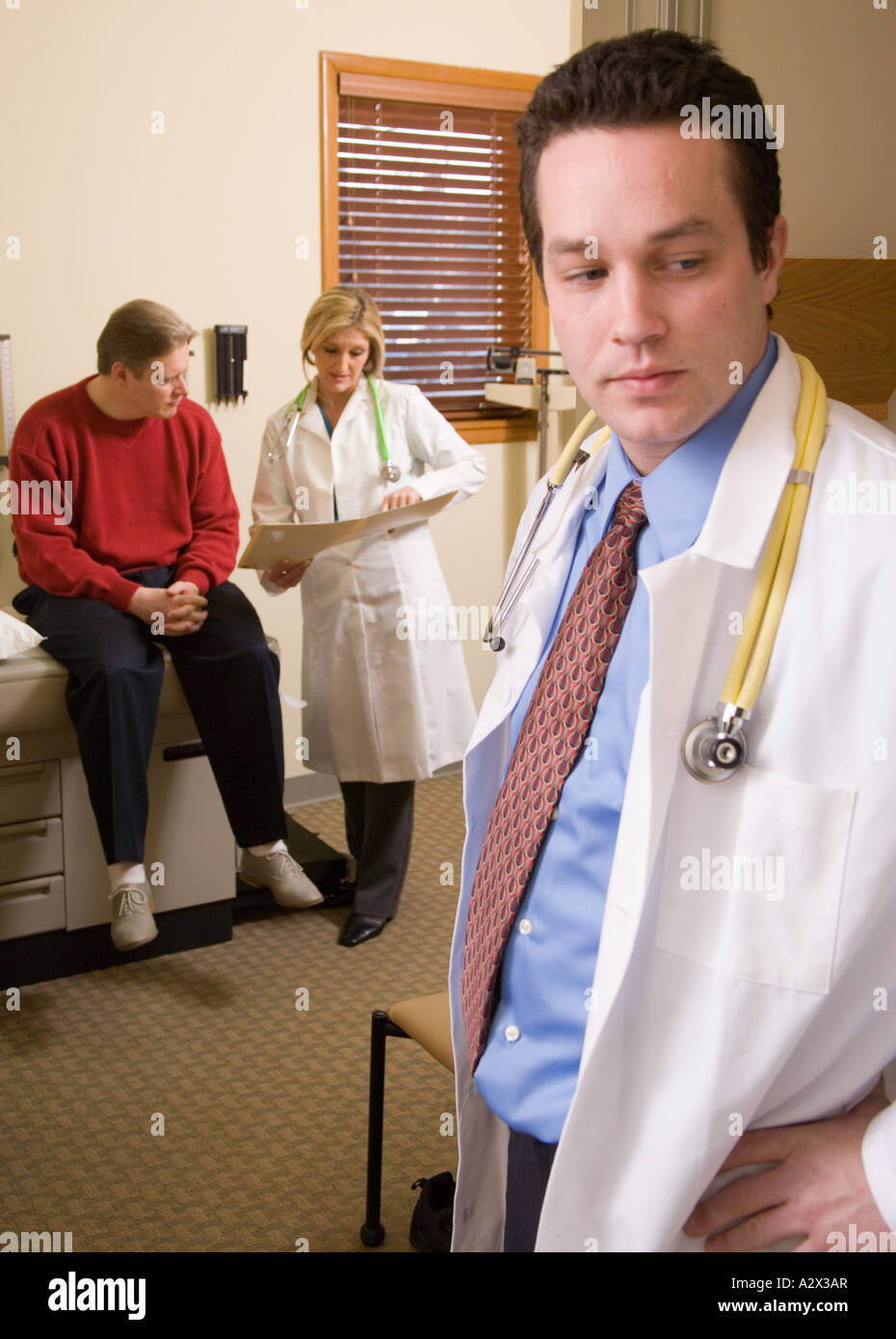 Doctor getting ready to enter exam room as a nurse talks to the patient ...