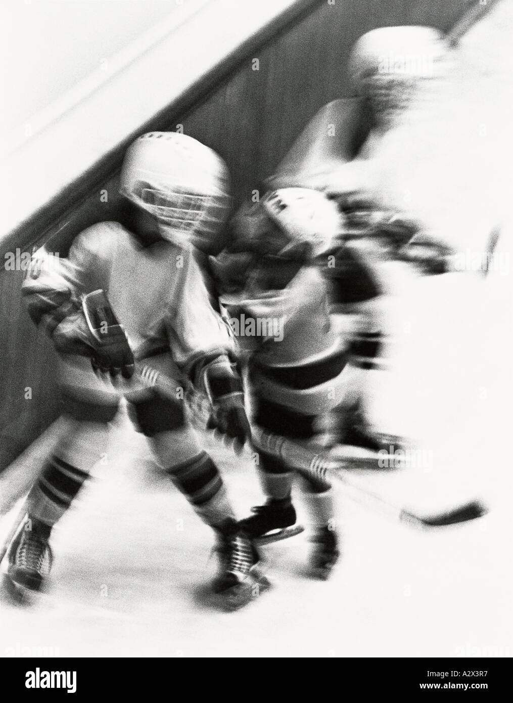 Motion blurred black and white image of three players in children's ice ...