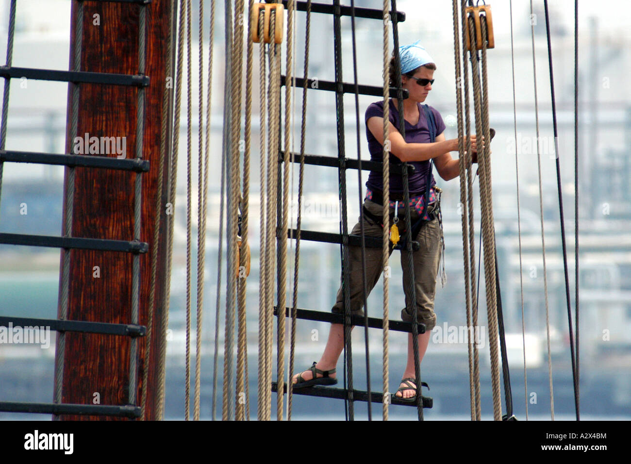 Female crew member onboard a tall masted ship working high up in the ...