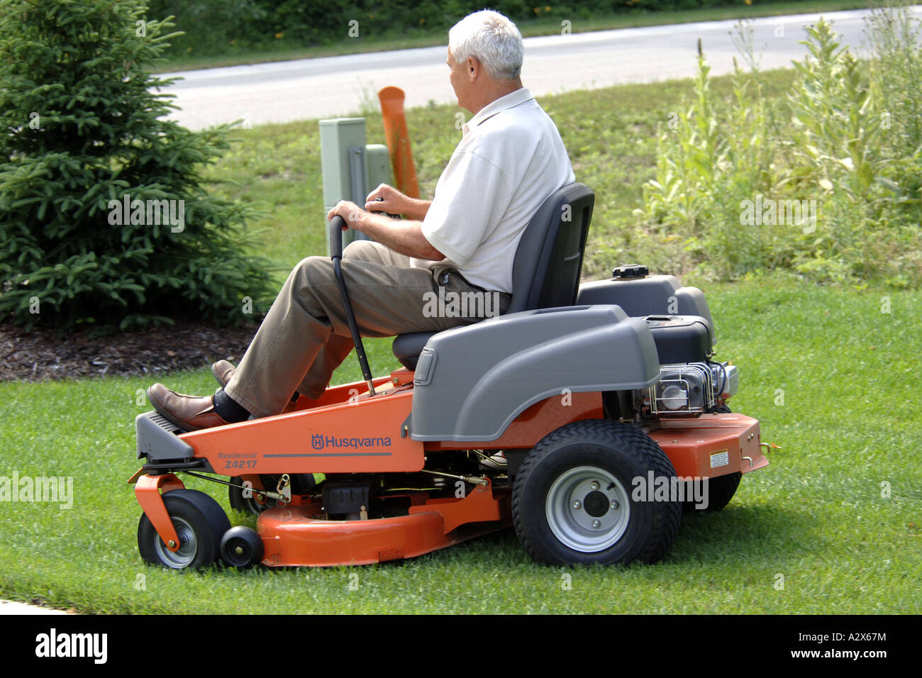 Senior Male cutting his lawn with a Zero-turn riding mower Stock Photo ...