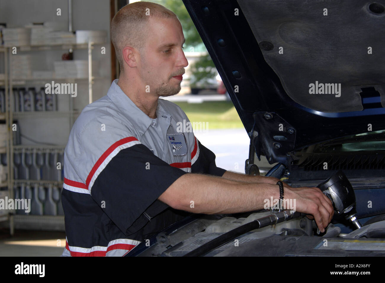 Male Vehicle Technician working on a vehicle's engine at a Quick ...