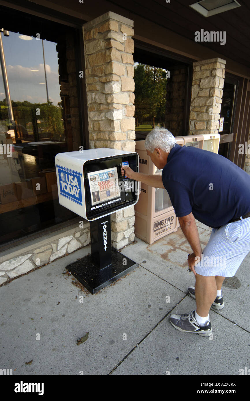 An adult male purchasing a newspaper from a vending machine Stock Photo ...