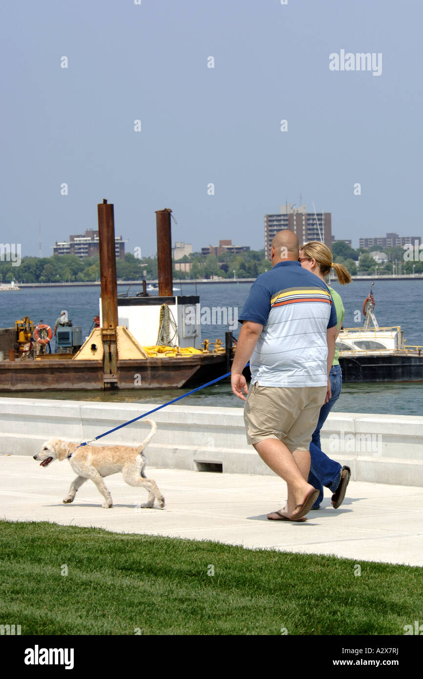 Two adult people taking their dog for a walk Stock Photo - Alamy