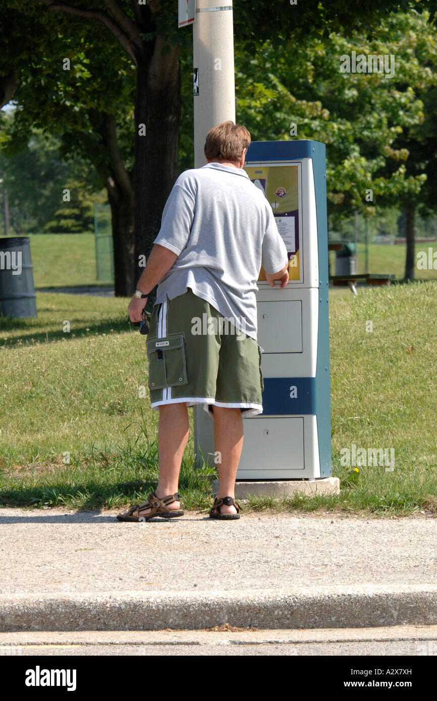 Adult male dopping coins into a parking bay meter machine Stock Photo ...