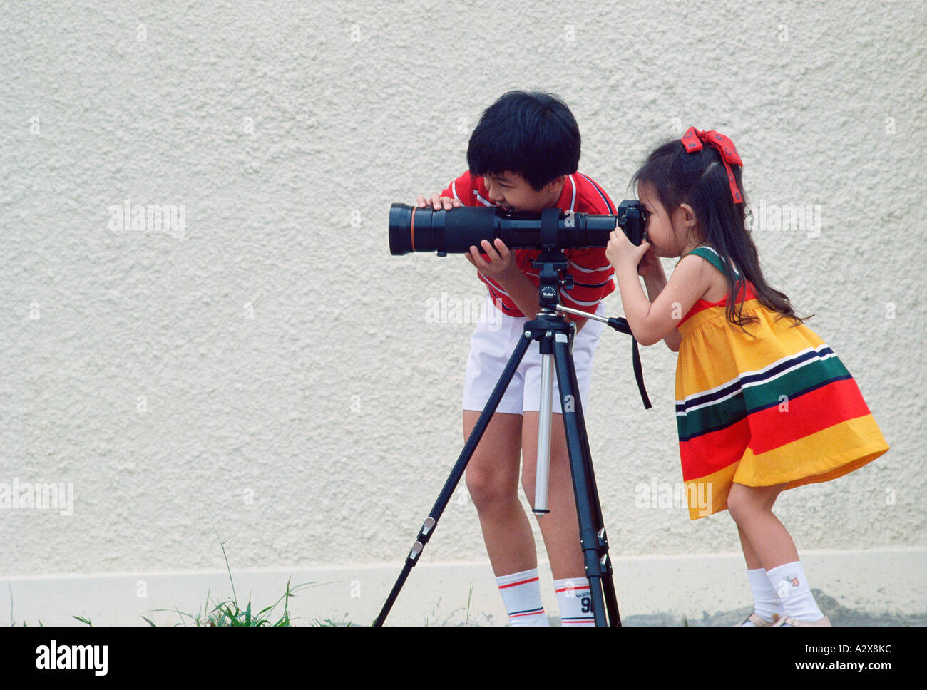 Singapore. Children. Little boy & girl looking through camera lens on ...