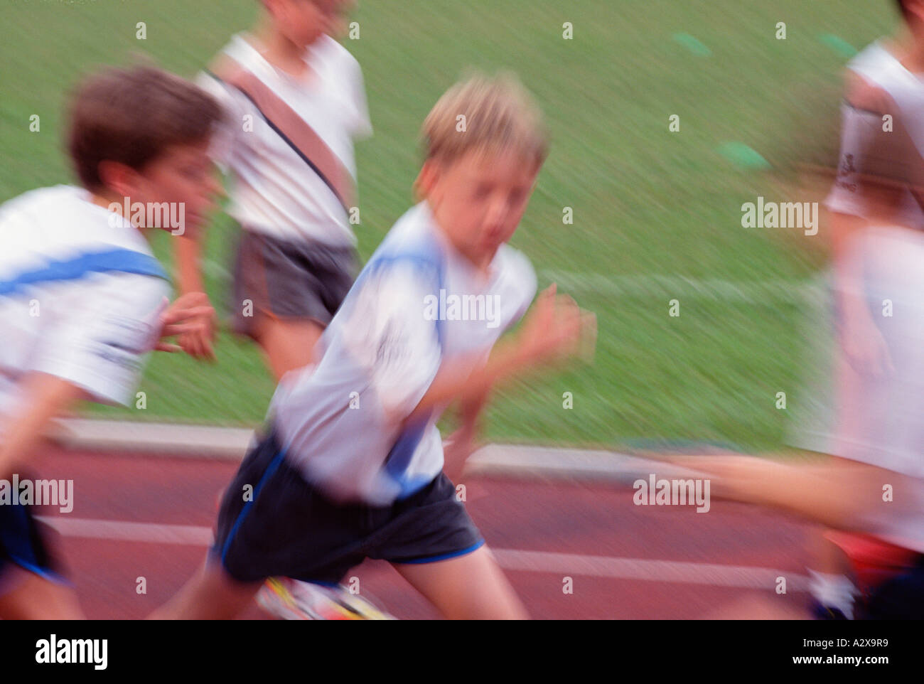 Outdoor closeup movement impression of school boys running on track ...