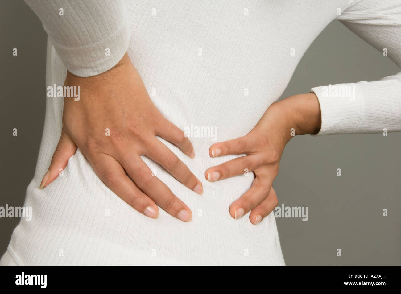 Woman with hands on back Stock Photo - Alamy