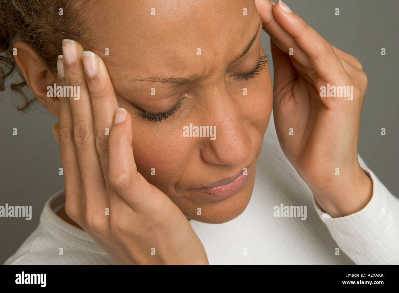 Woman holding head in hands Stock Photo - Alamy