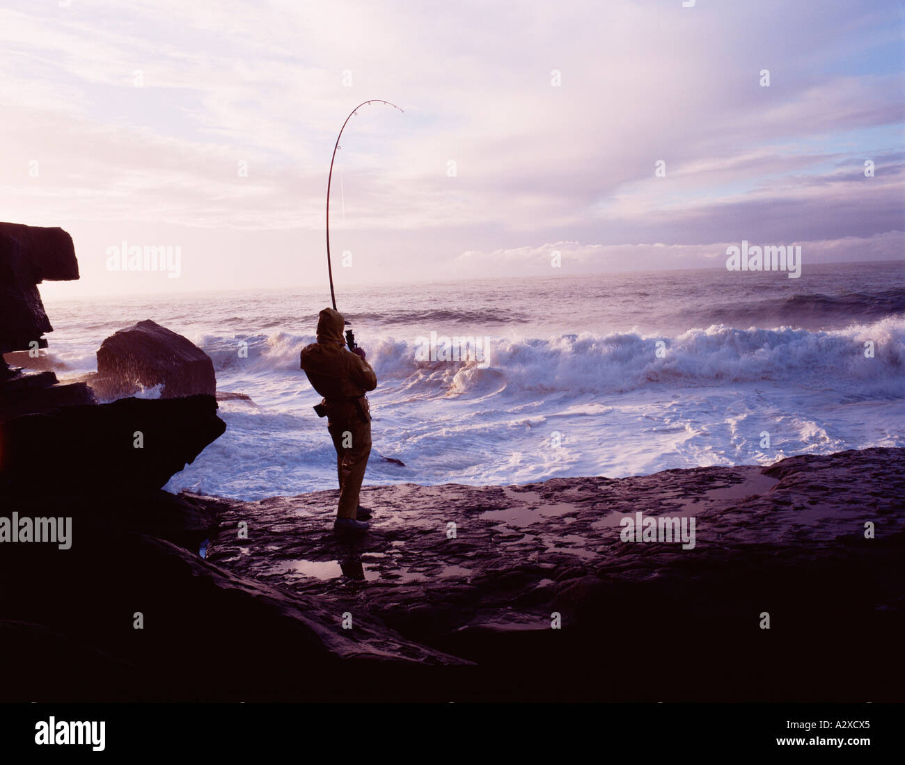 Man sea fishing from rocks Stock Photo - Alamy