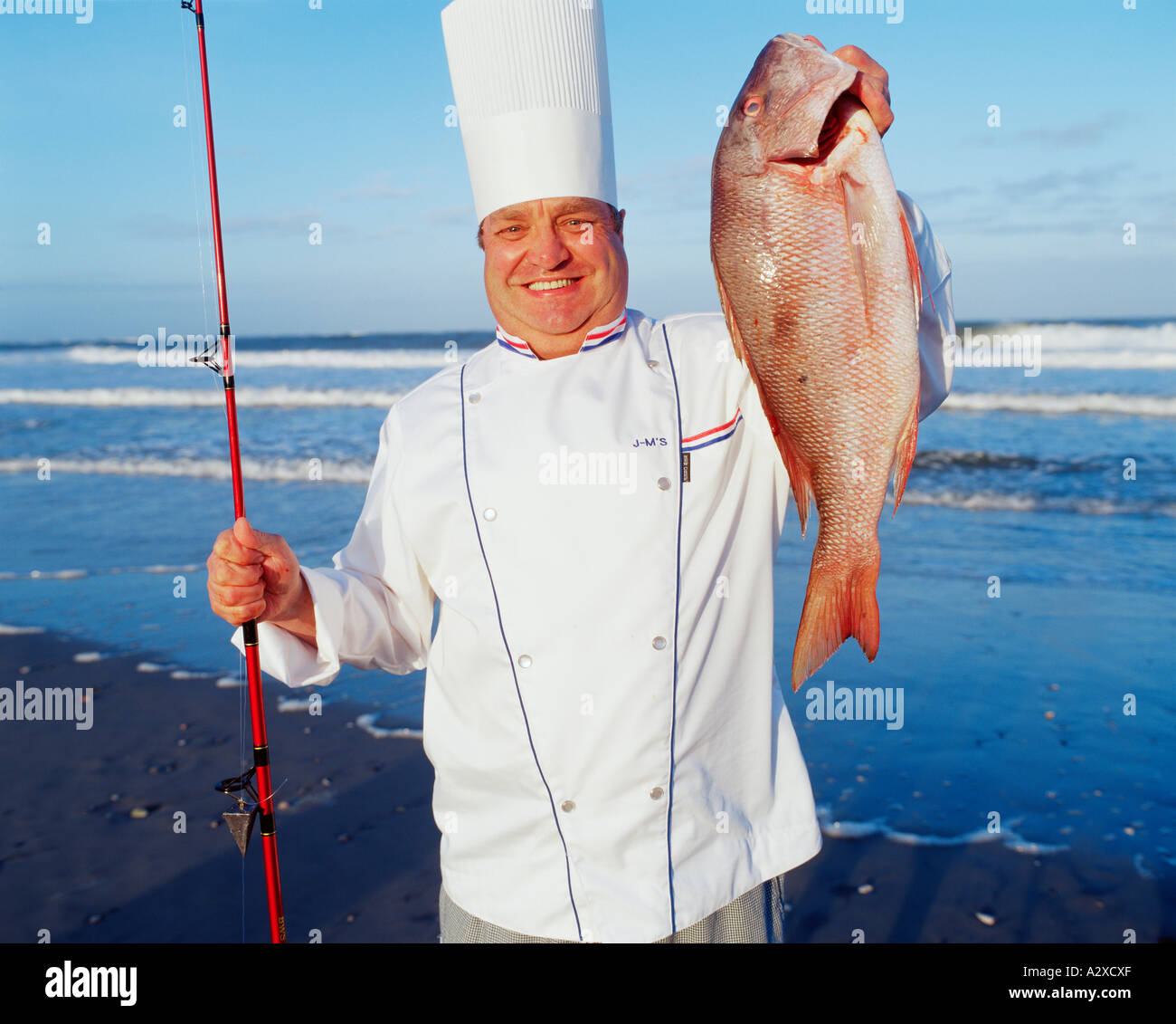 Man in chef's uniform at the beach holding freshly caught fish Stock ...
