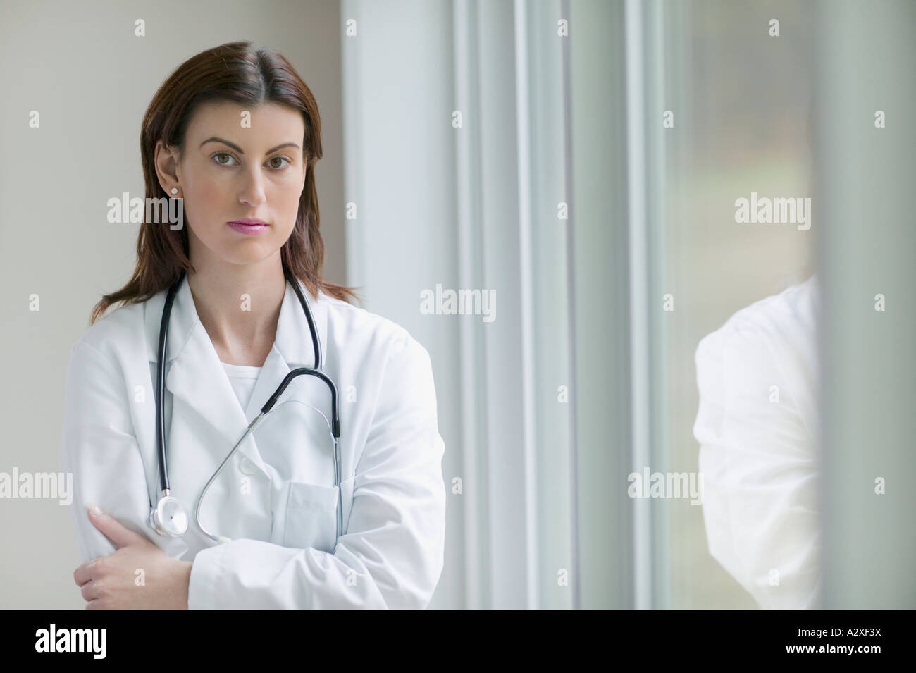 Female doctor standing next to window indoors Stock Photo - Alamy