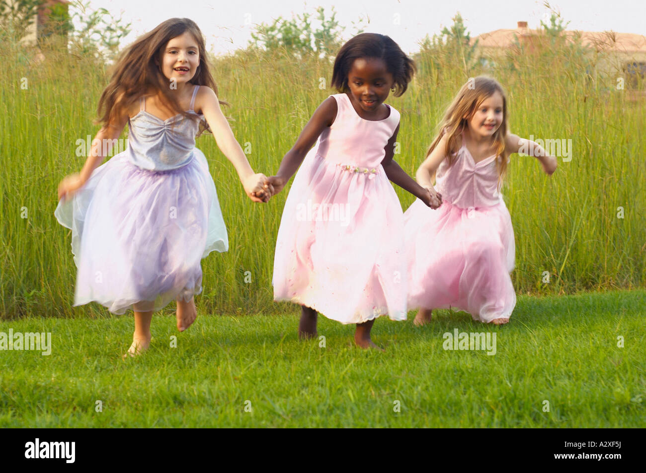 Young girls wearing party dresses and running in field Stock Photo - Alamy