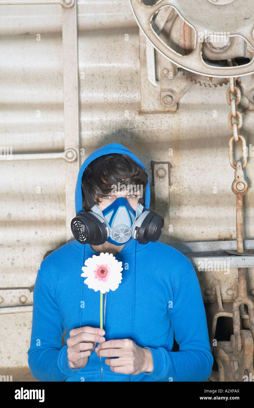 Young man wearing air filter mask and holding flower Stock Photo - Alamy