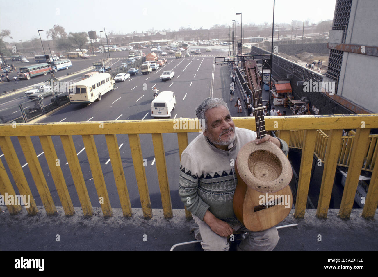 homeless man sitting on the street holding a guitar and a straw hat ...