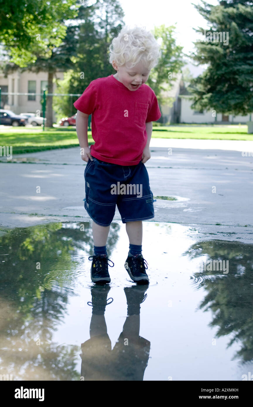 Toddler Boy Splashes In Puddle On Town Playground Stock Photo - Alamy