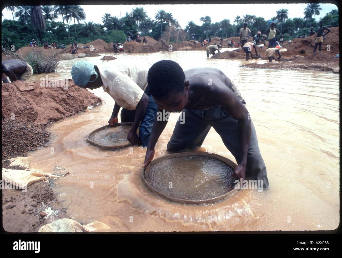Men standing in water is diamond panning near Portoru in Sierra Leone ...