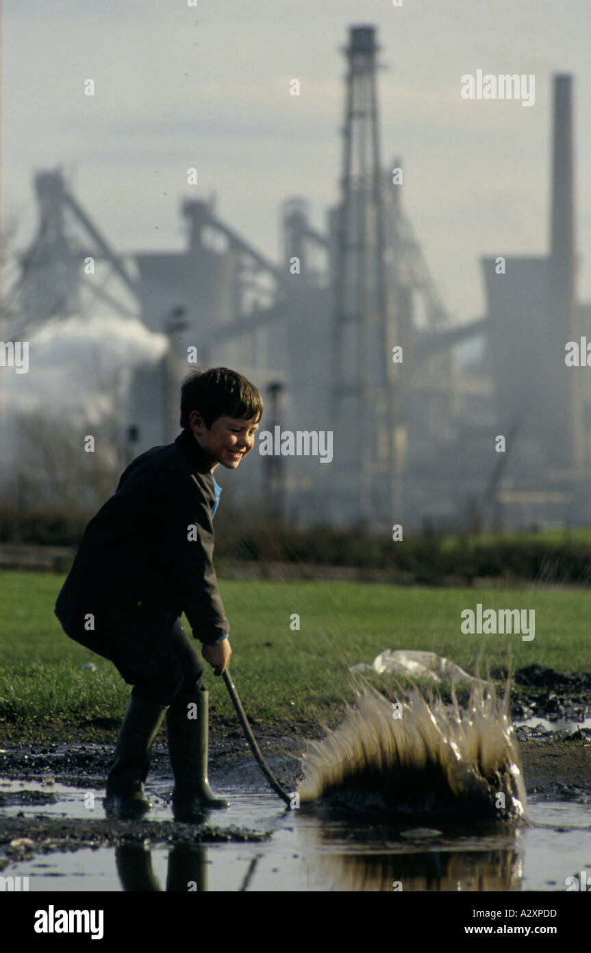 Motherwell, Scotland. A boys splashes in a puddle. Behind him ...