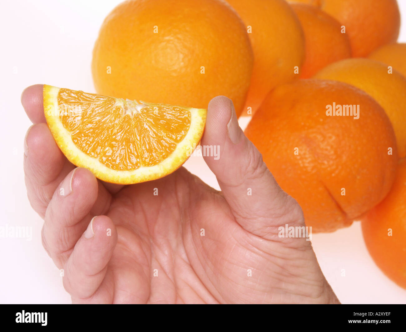 Hand with orange wedge Stock Photo - Alamy