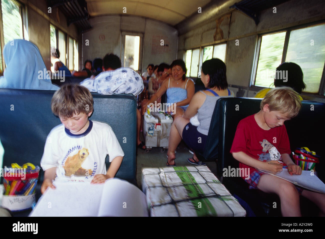 Two young boy tourists travel on the Tenom train in Borneo, with slow ...