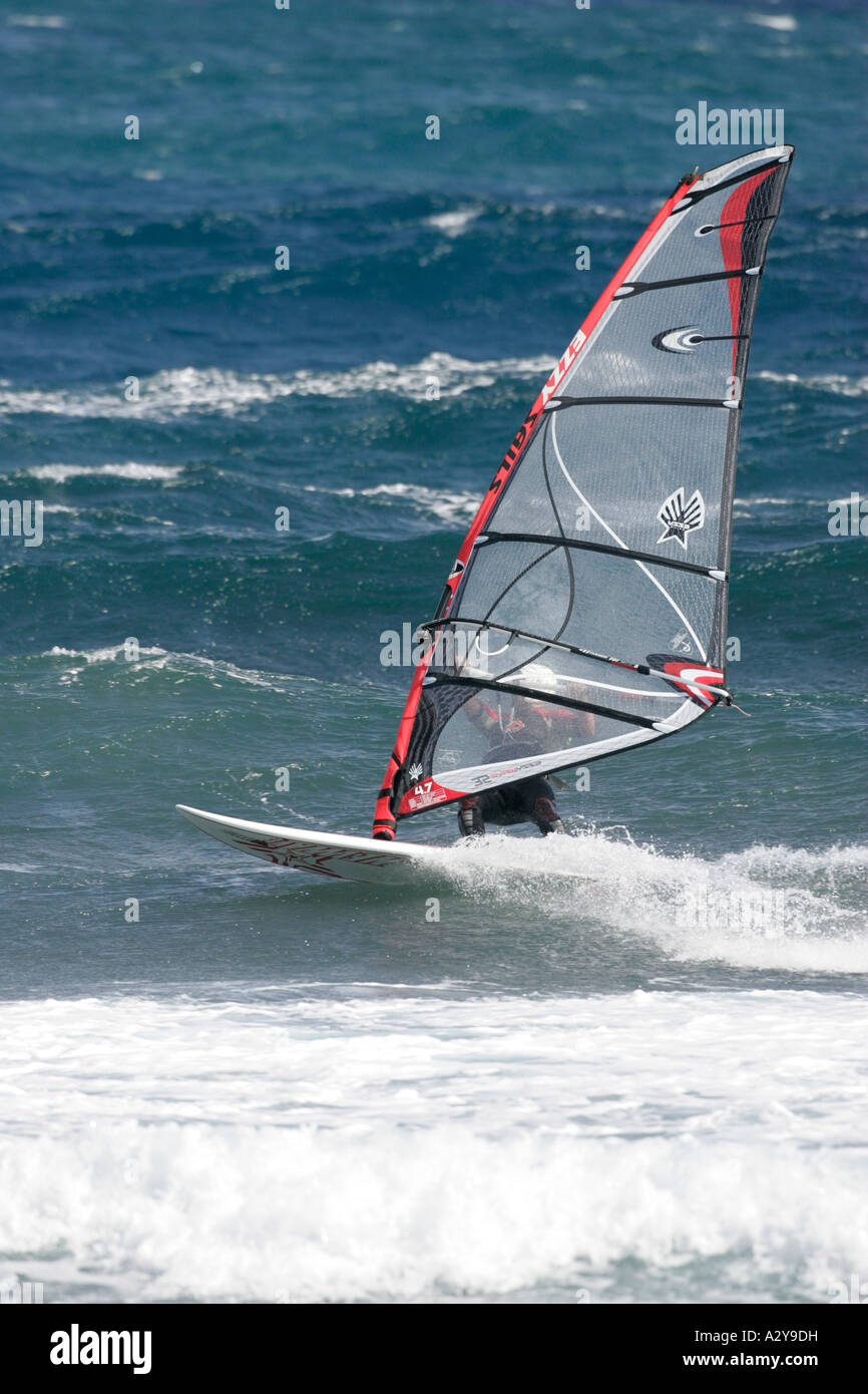 male windsurfer in wetsuit and helmet rides his board at speed in the ...