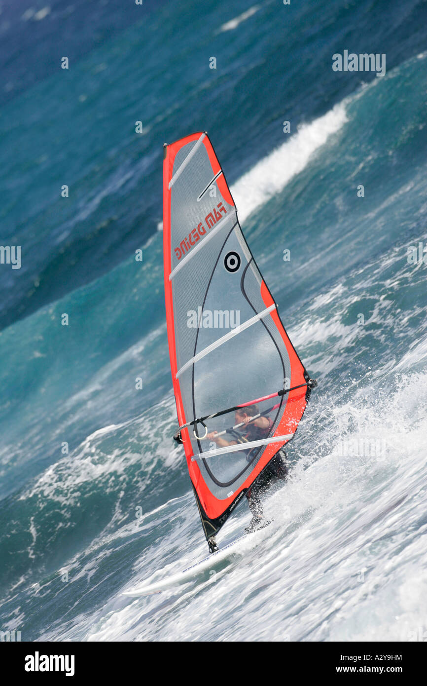 windsurfer in wetsuit rides their board at speed through the waves in ...