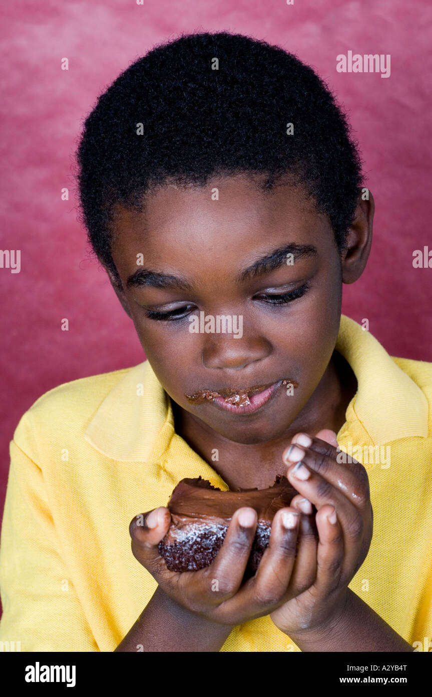 Young black boy eating chocolate brownie Stock Photo - Alamy