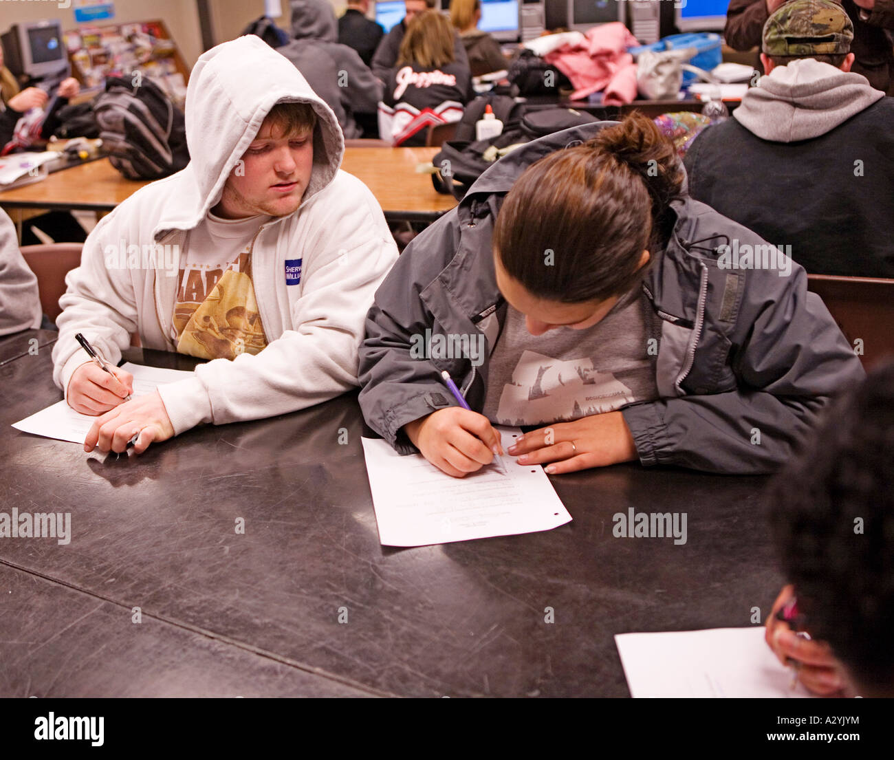 Image of a teenage boy looking at his neighbor s paper while taking a ...