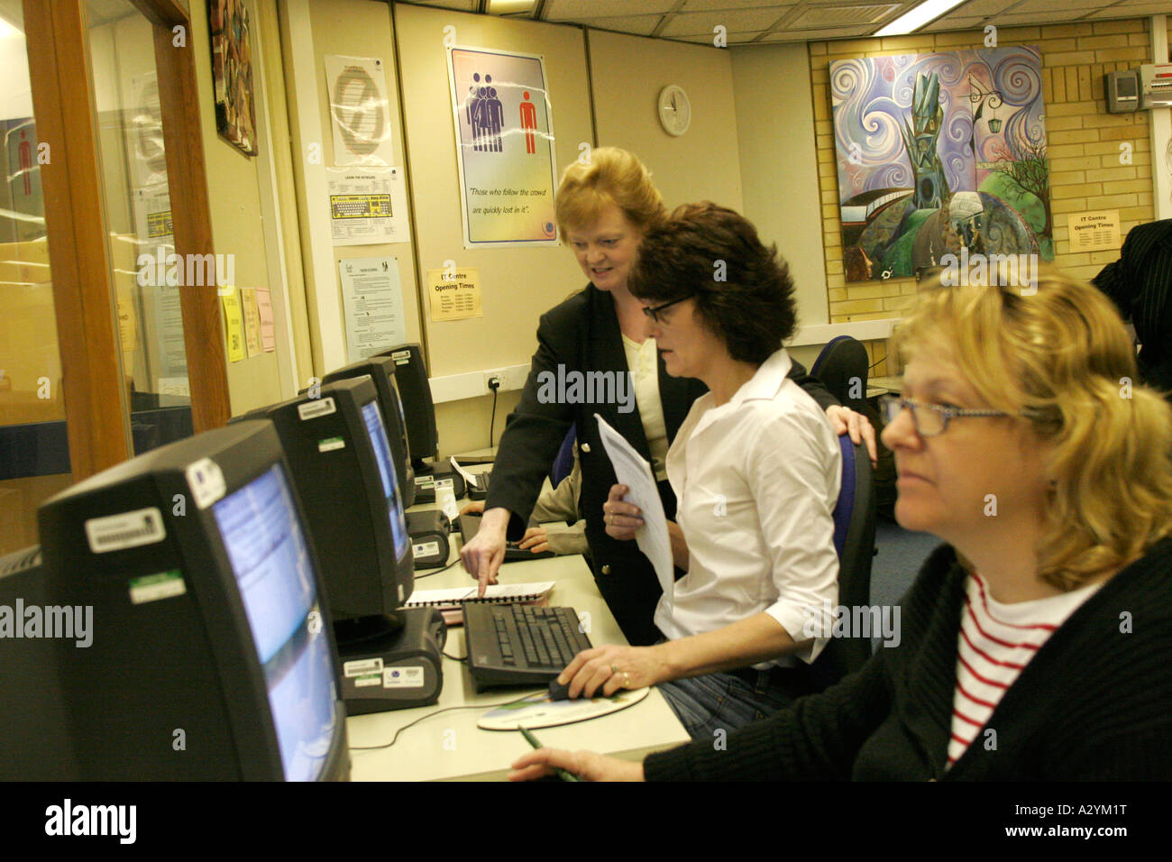 Mature female students with computer and instructor Stock Photo - Alamy