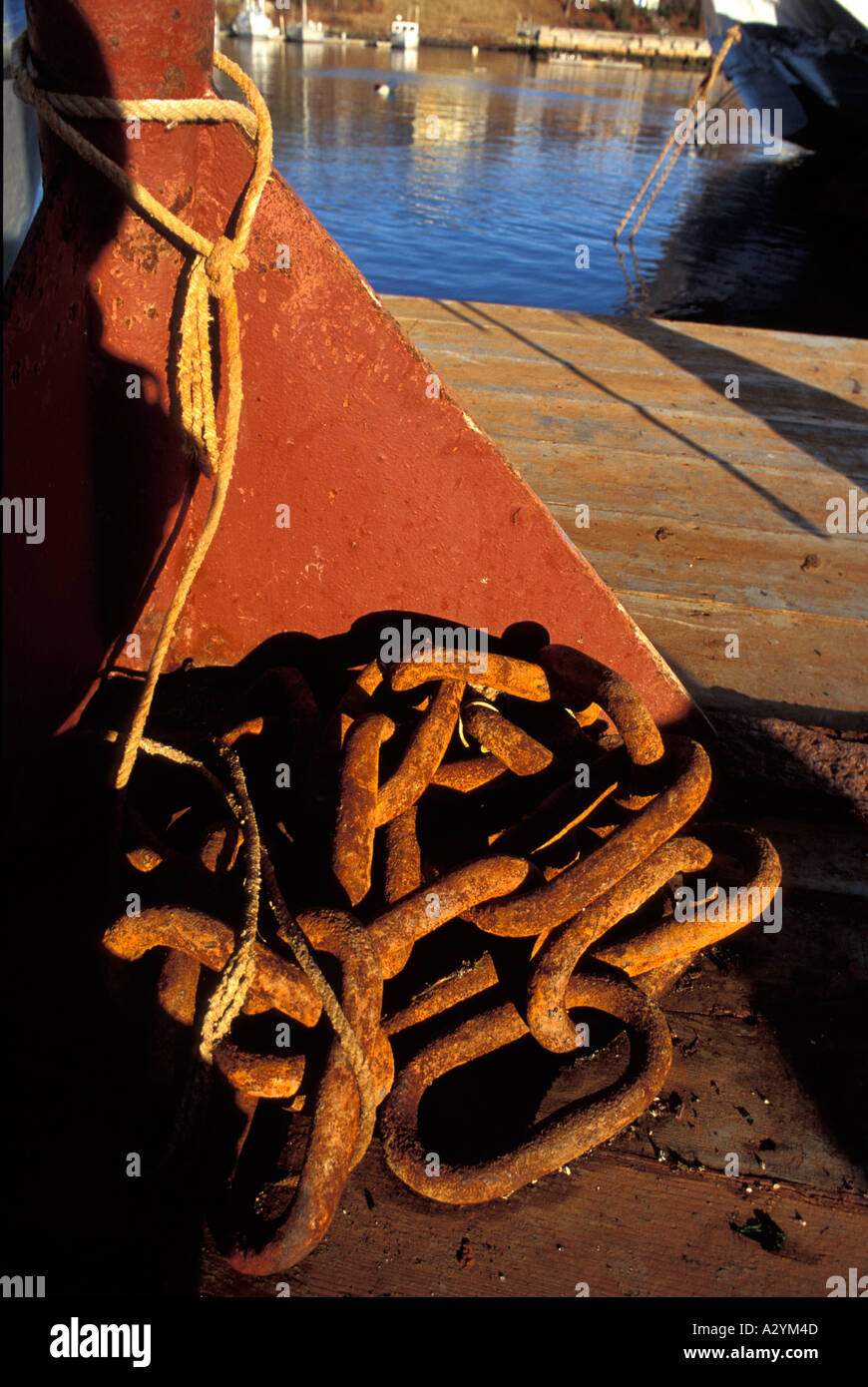Rusting anchor chain on dock with water in background Stock Photo - Alamy