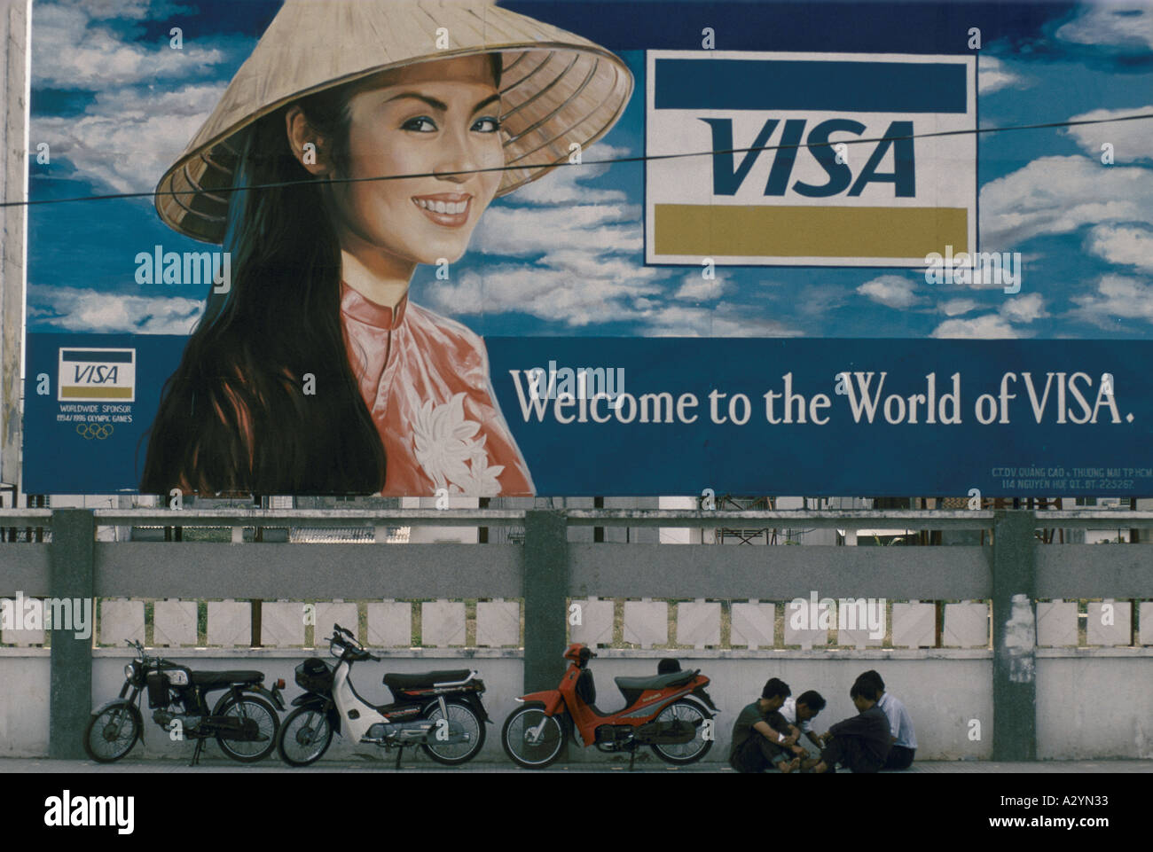 three men and three mopeds are underneath a visa advert with smiling ...