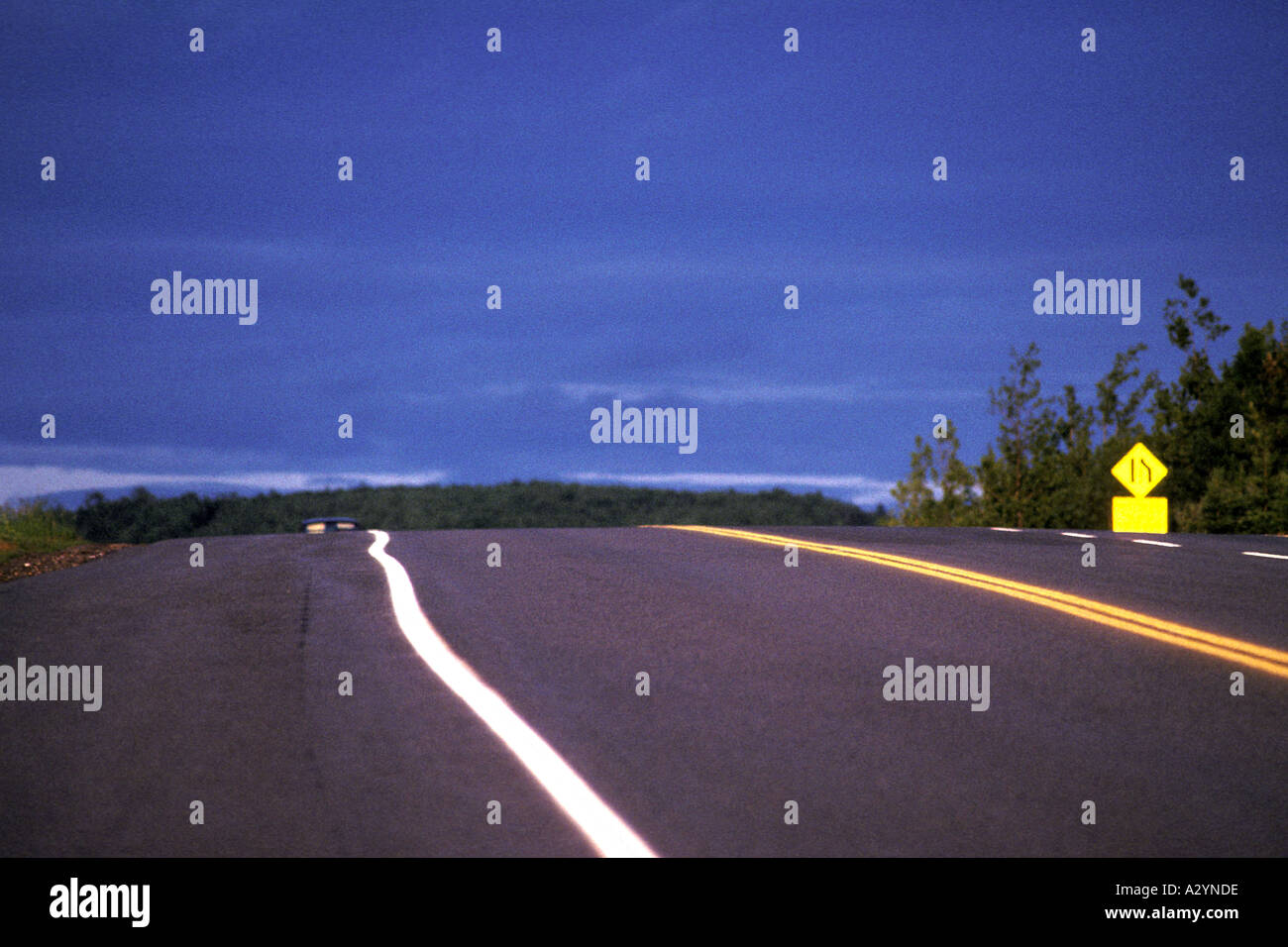 Open road at sunset with dark clouds in the distance and white line ...