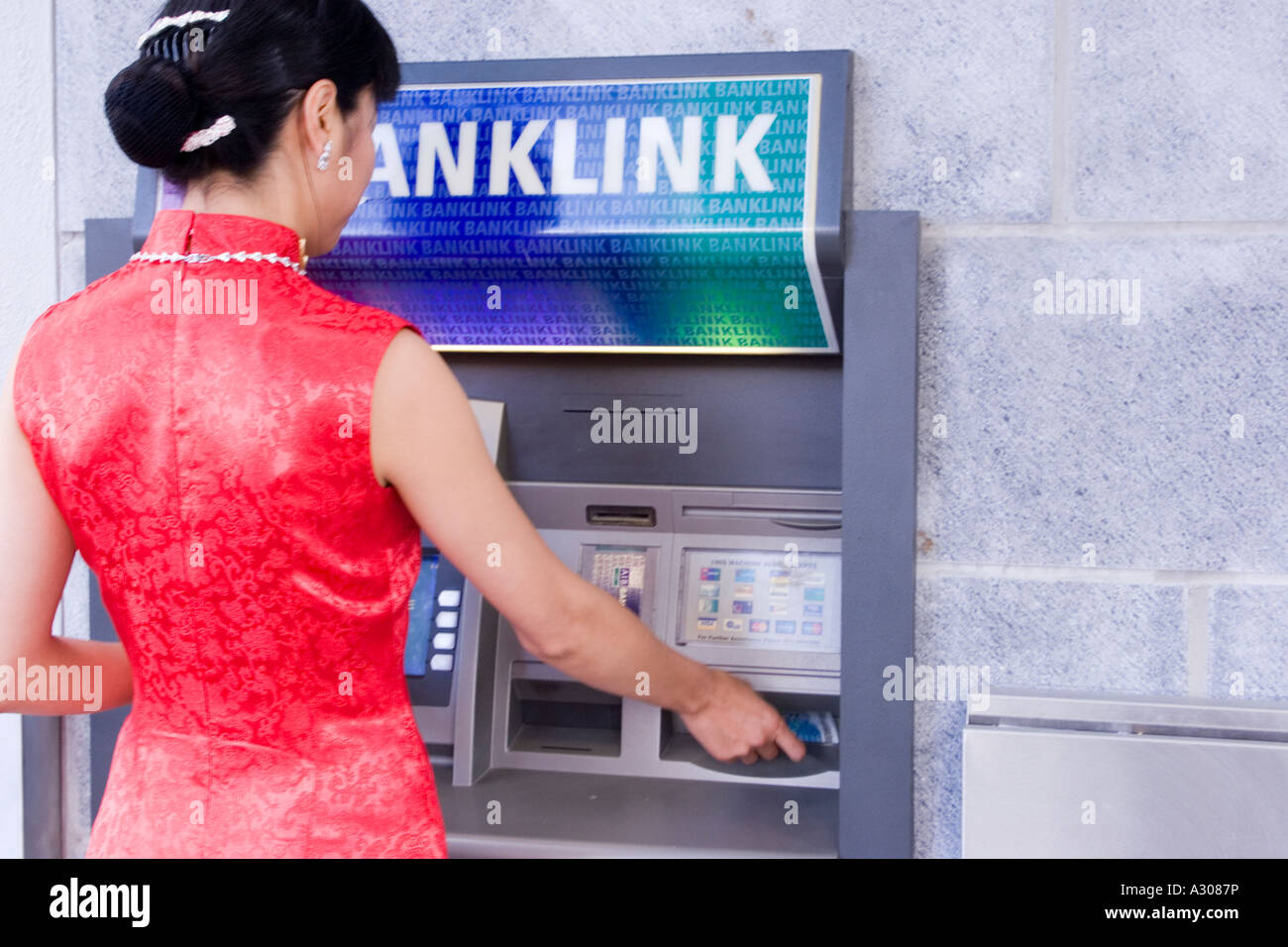 Rear view of a woman using bank ATM machine Stock Photo - Alamy