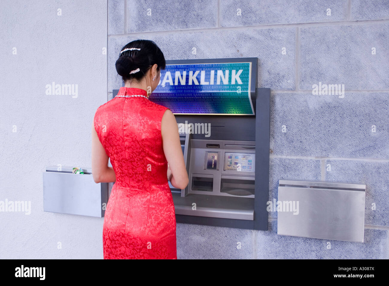Rear view of a woman using bank ATM machine Stock Photo - Alamy