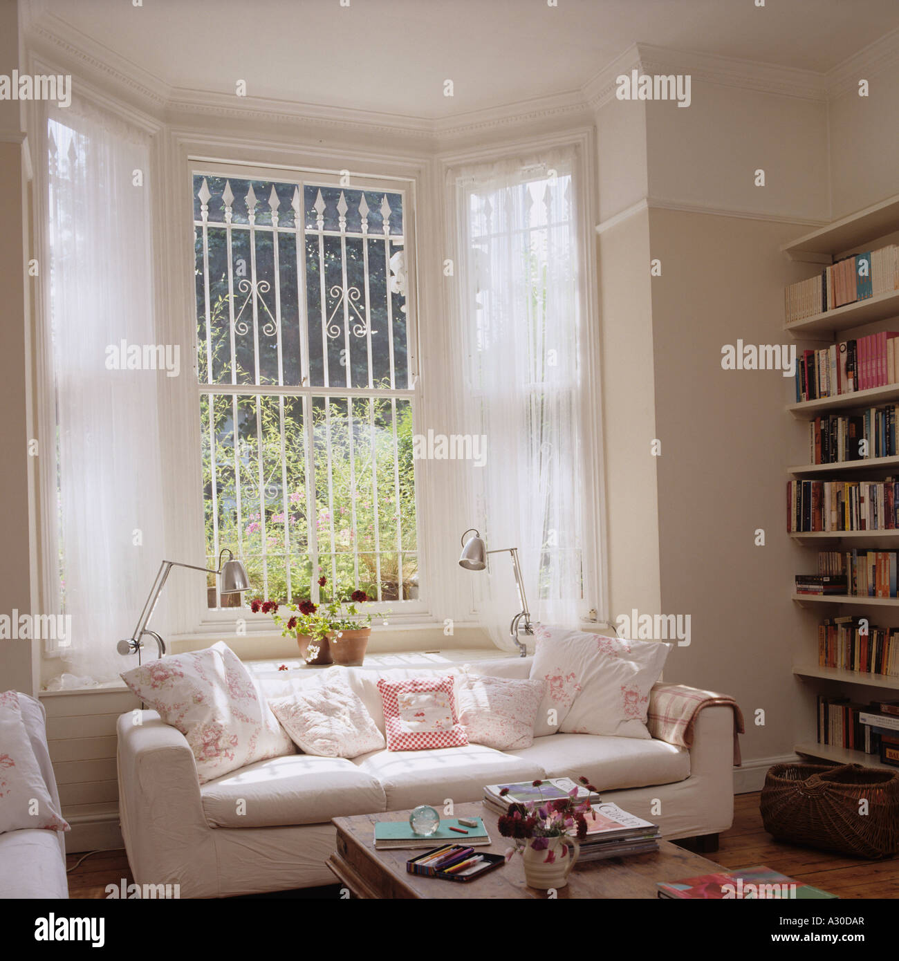 White sofa in bay window with bookcase Stock Photo - Alamy