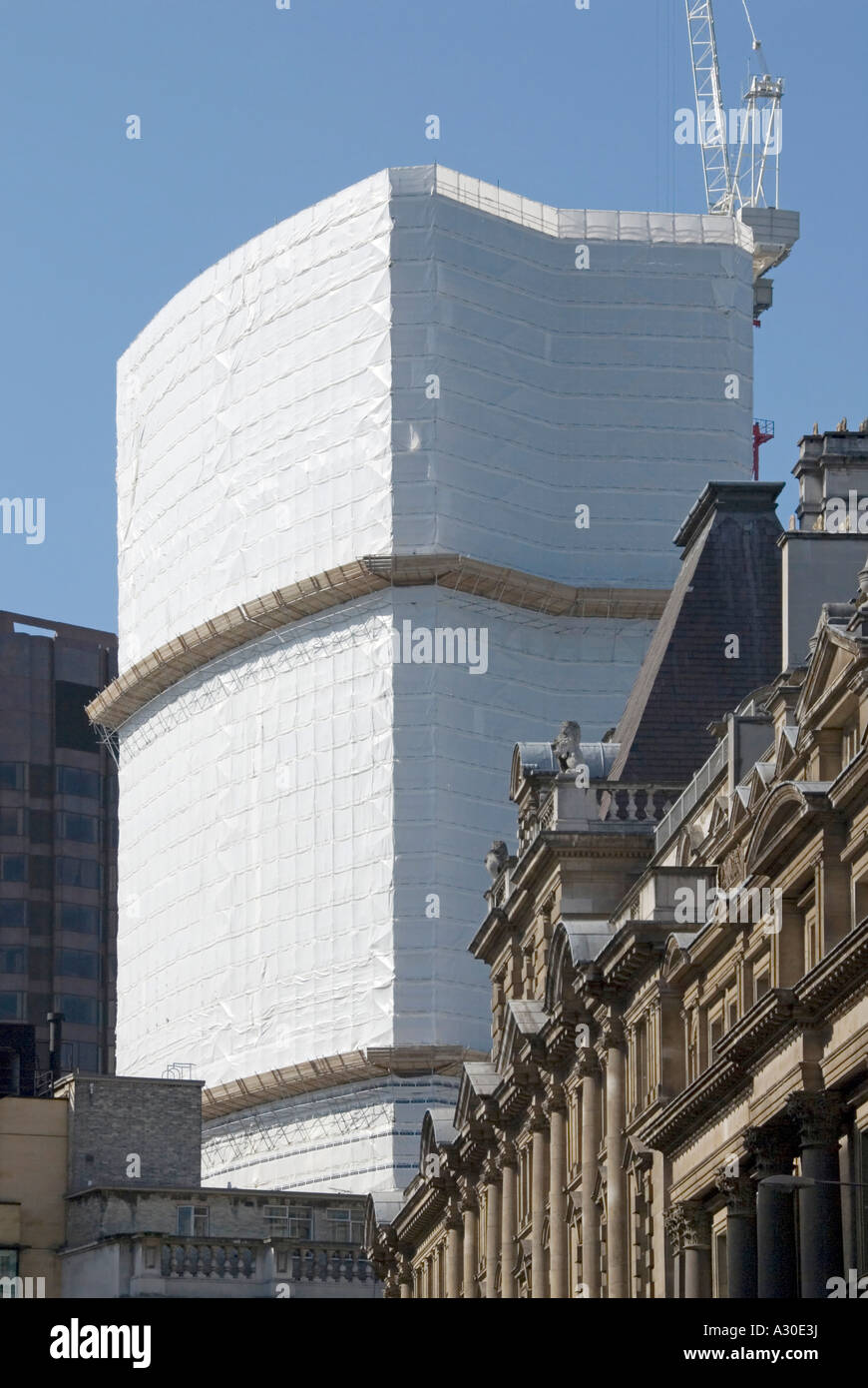Tall office block & scaffolding wrapped in cocoon of white plastic ...