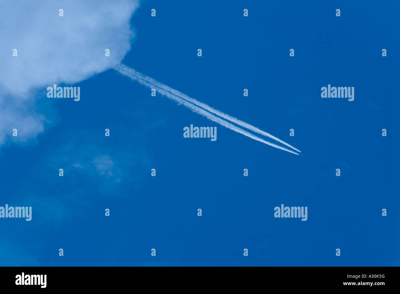 Jet plane with double contrail emerging from behind cumulus cloud Stock ...