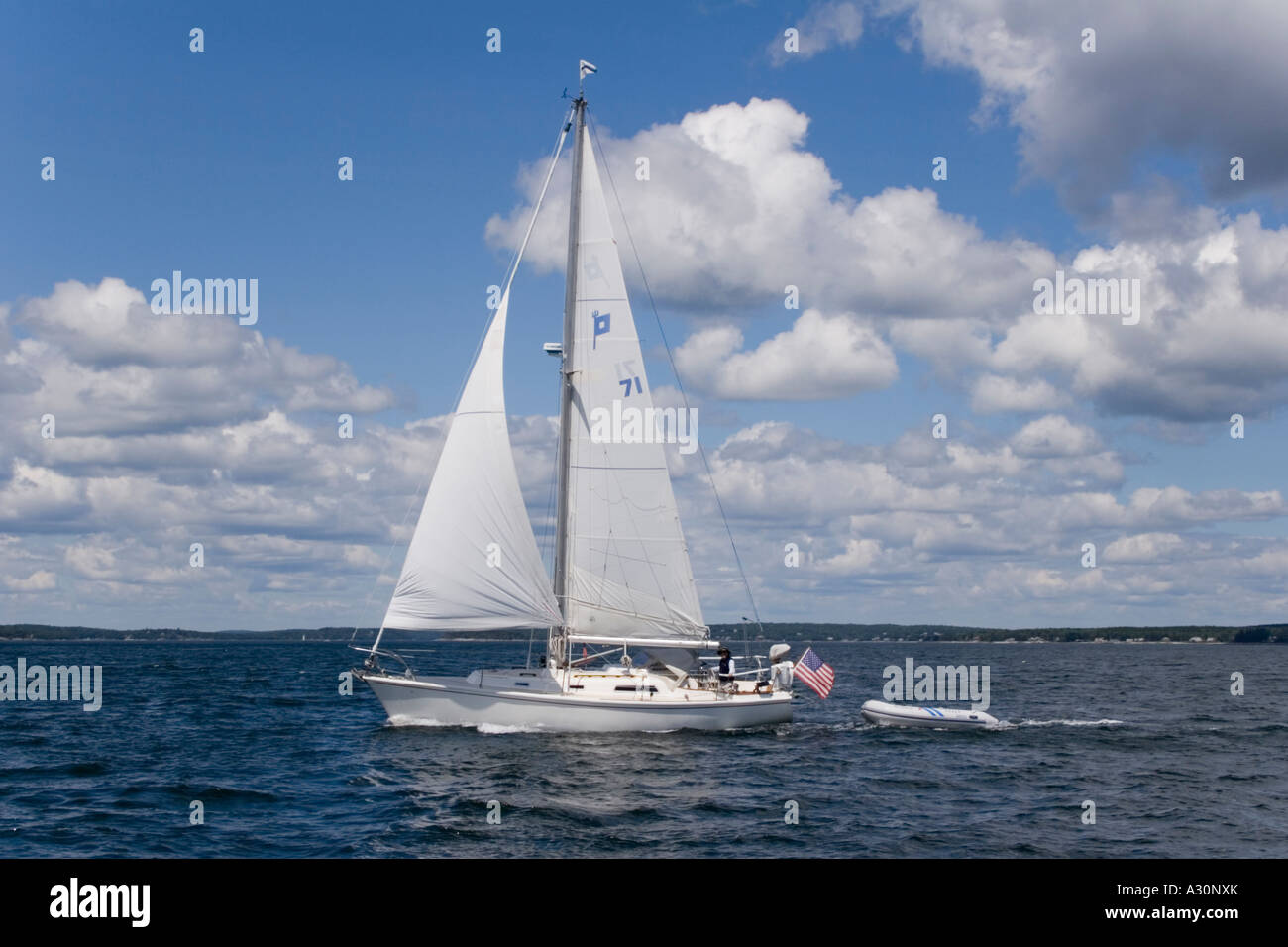 A cruising sloop under sail with a reefed jib in the waters of ...