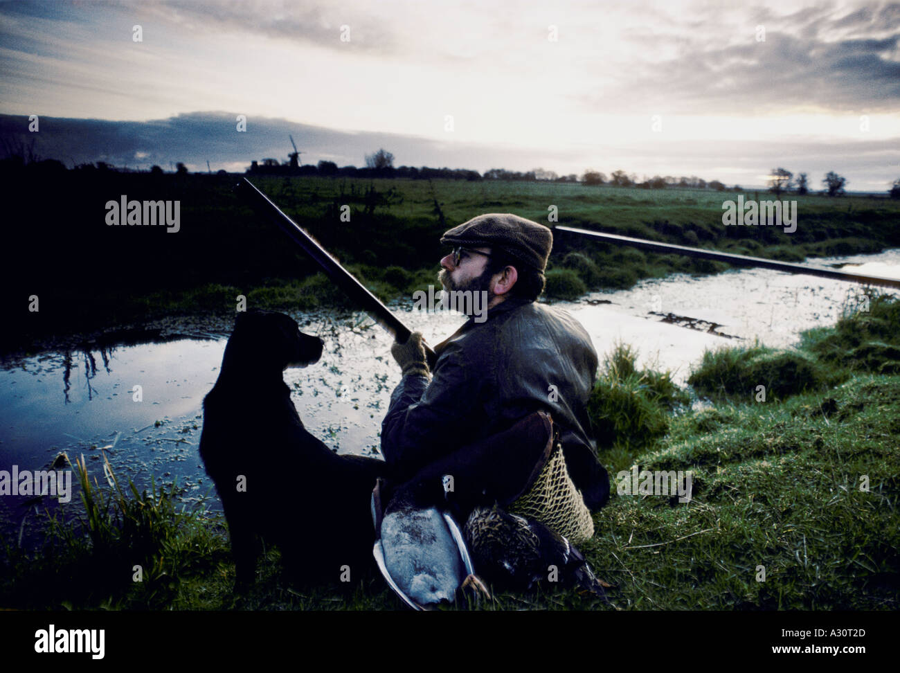 man duck shooting holding double barreled shot gun sitting on the banks ...